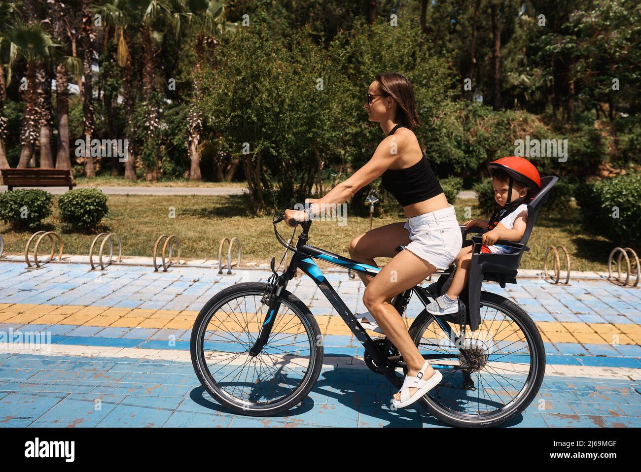 Active mother and child riding a bike together on outdoors background ...
