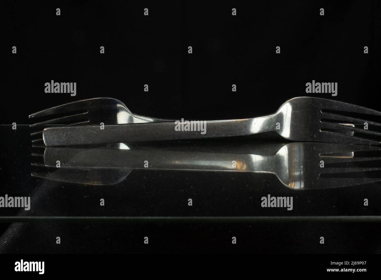 two crossing crossing silver dinner forks reflected and isolated on a ...