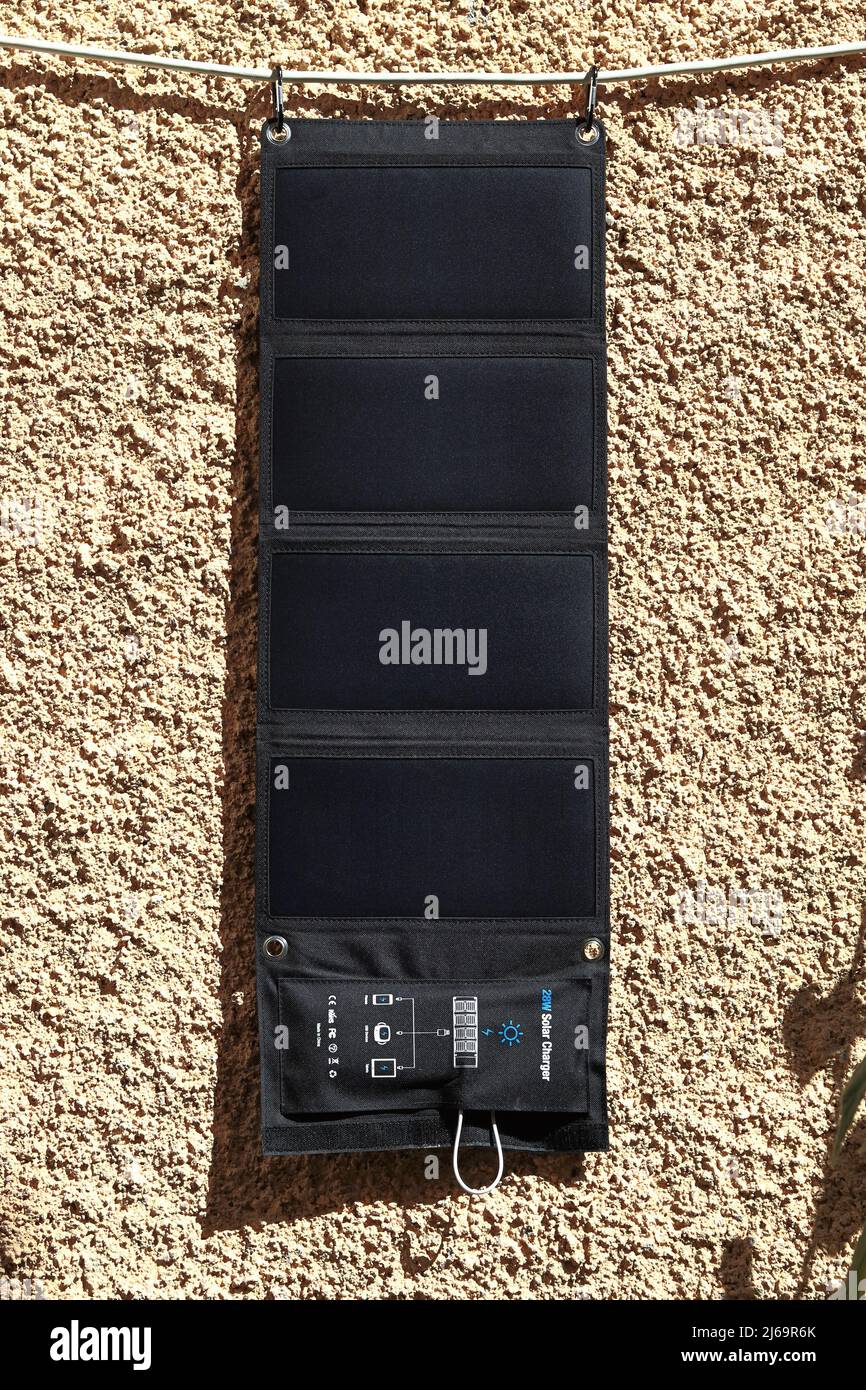 A solar panel charging an electronic device. Against a wall and full ...