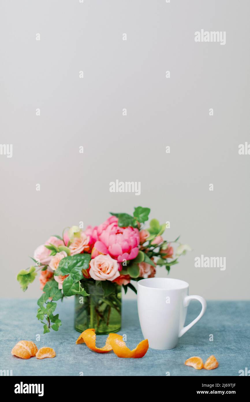 pink and peach flower centerpiece with white coffee mug and clementine ...