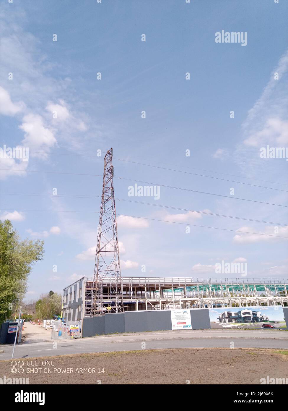 A modern office building under construction with a electricity pylon in ...