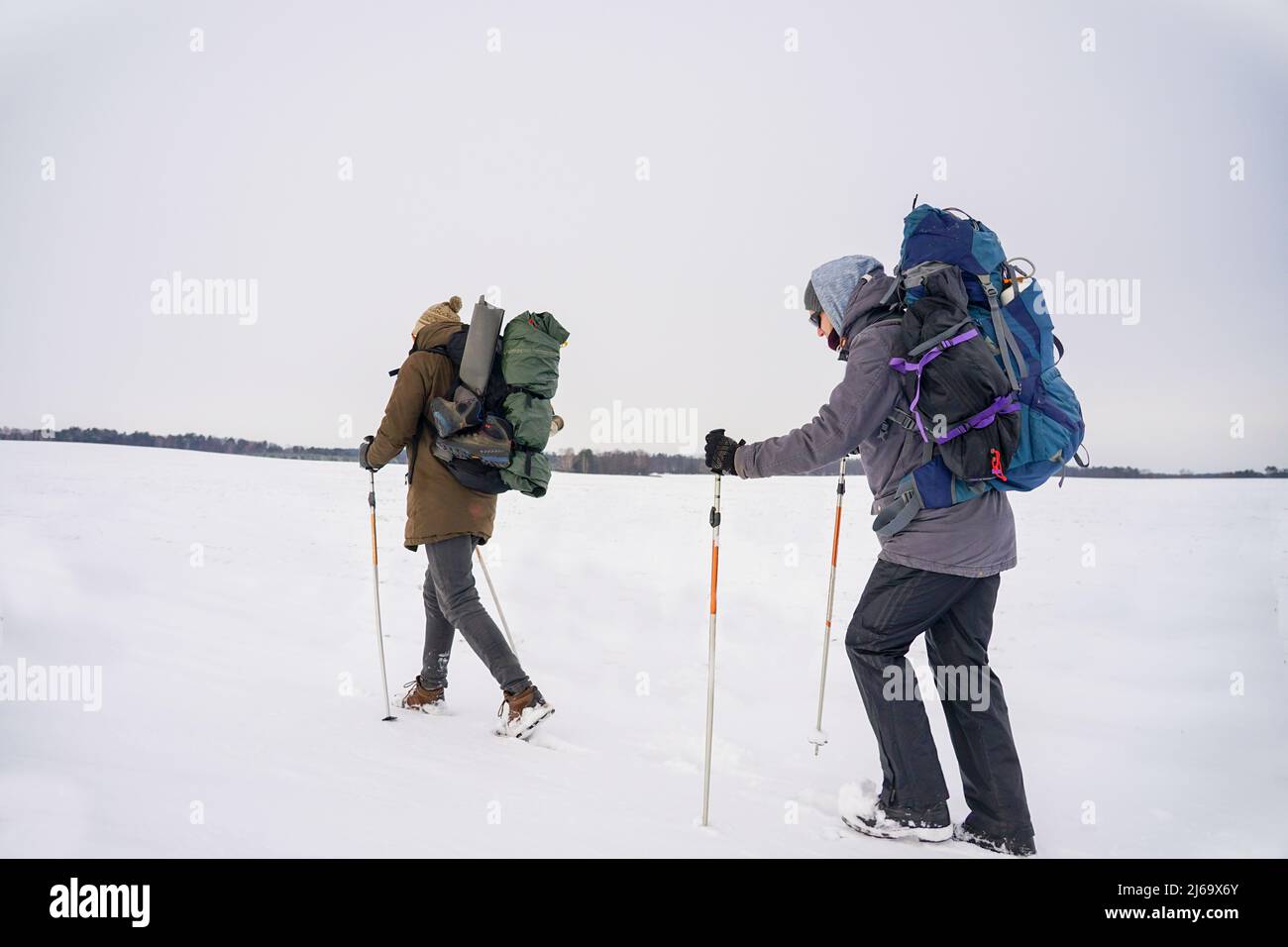 Two guys walk through loose snow during a winter expedition. They carry ...