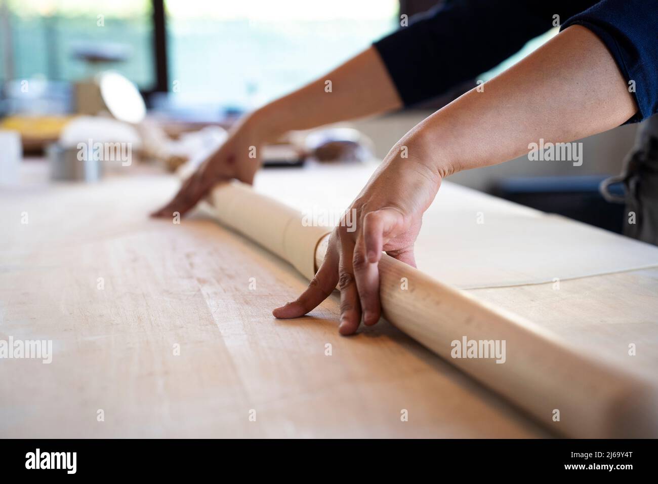 Close up of female hands working with rolling-pin for italian fresh ...