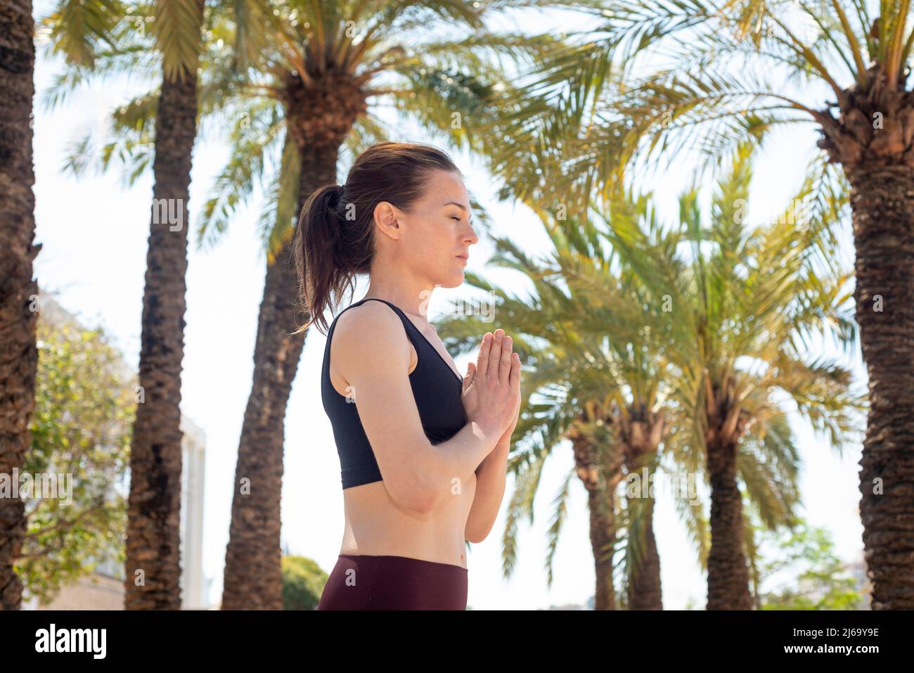 Fit female with the palms together in the parkpracticing yoga and ...
