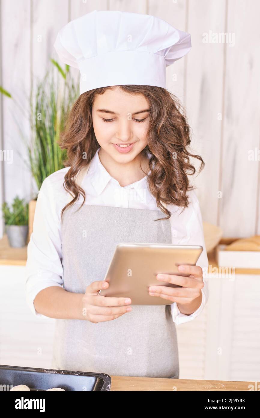 Young girl cooking at kitchen. Curly pretty child portrait. Chef ...