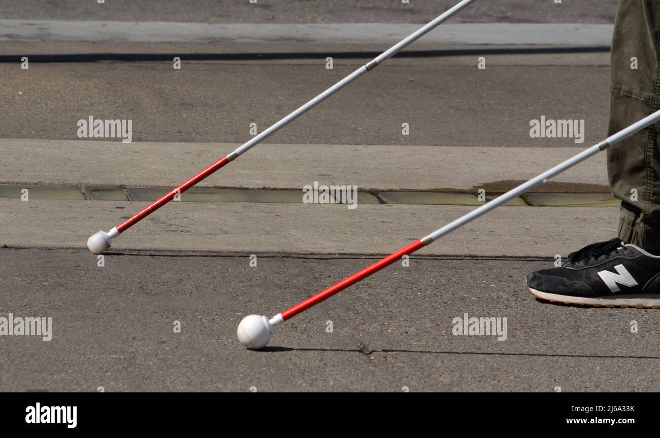 Two people with visual impairments use a white cane to help them ...