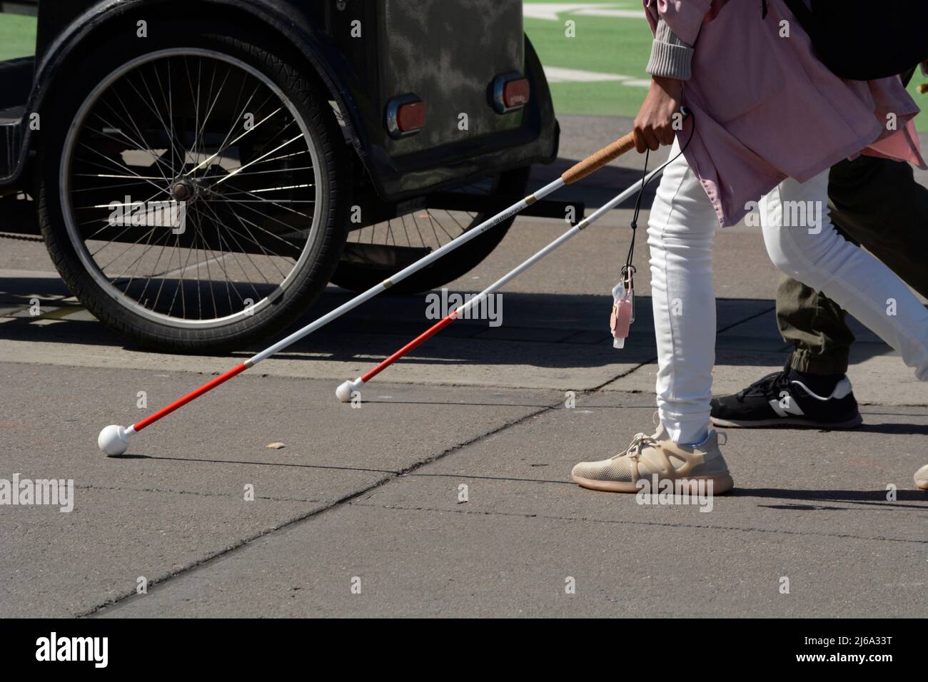 Two people with visual impairments use a white cane to help them ...