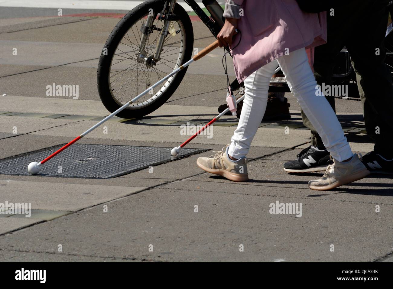 Two people with visual impairments use a white cane to help them ...