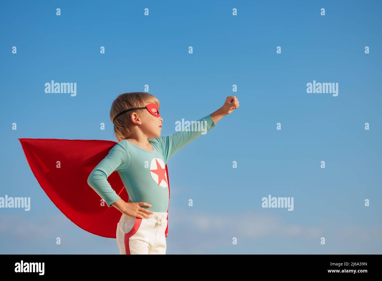 Superhero child playing outdoor. Super hero kid against blue summer sky ...
