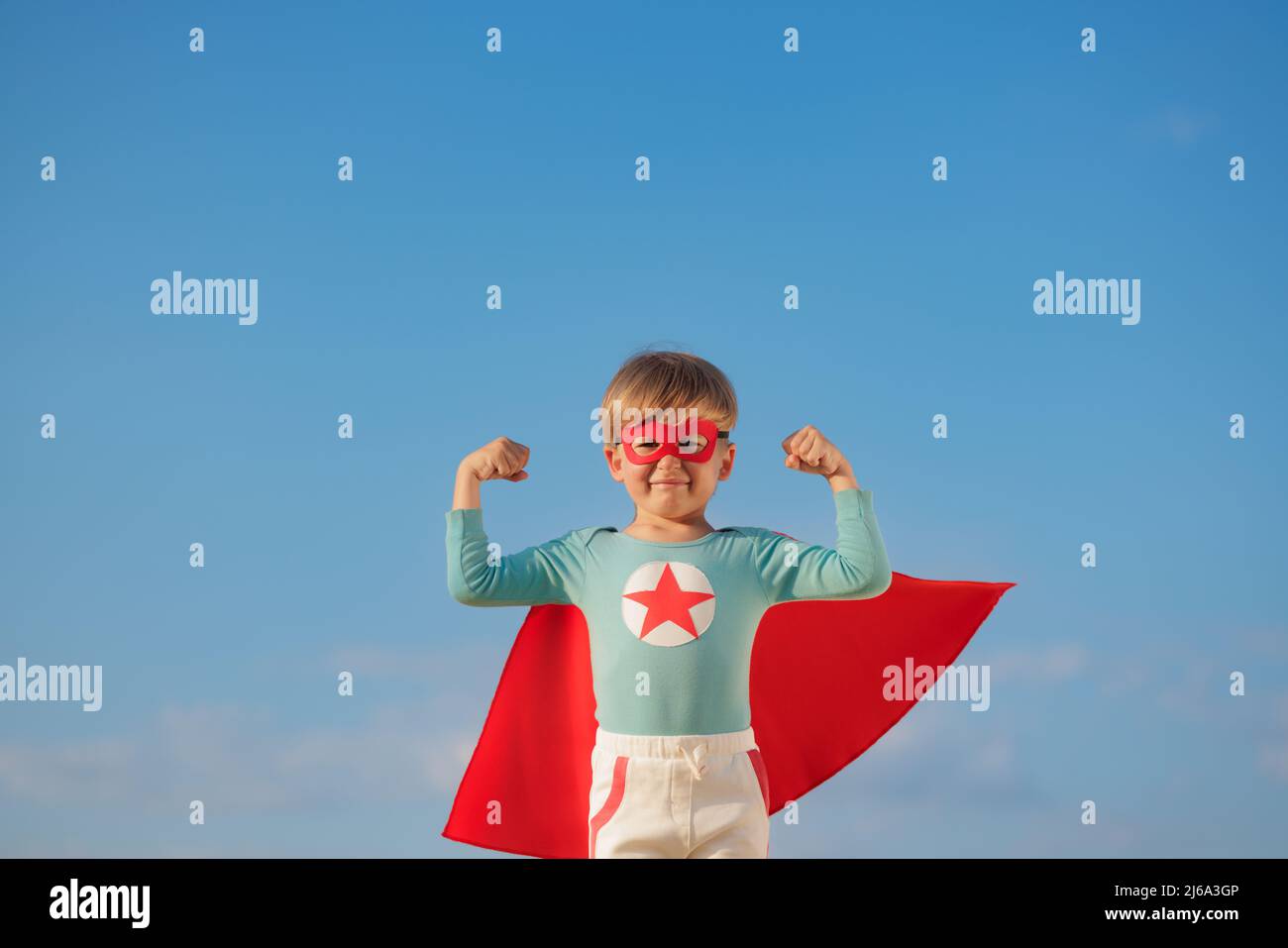 Superhero child playing outdoor. Super hero kid against blue summer sky ...