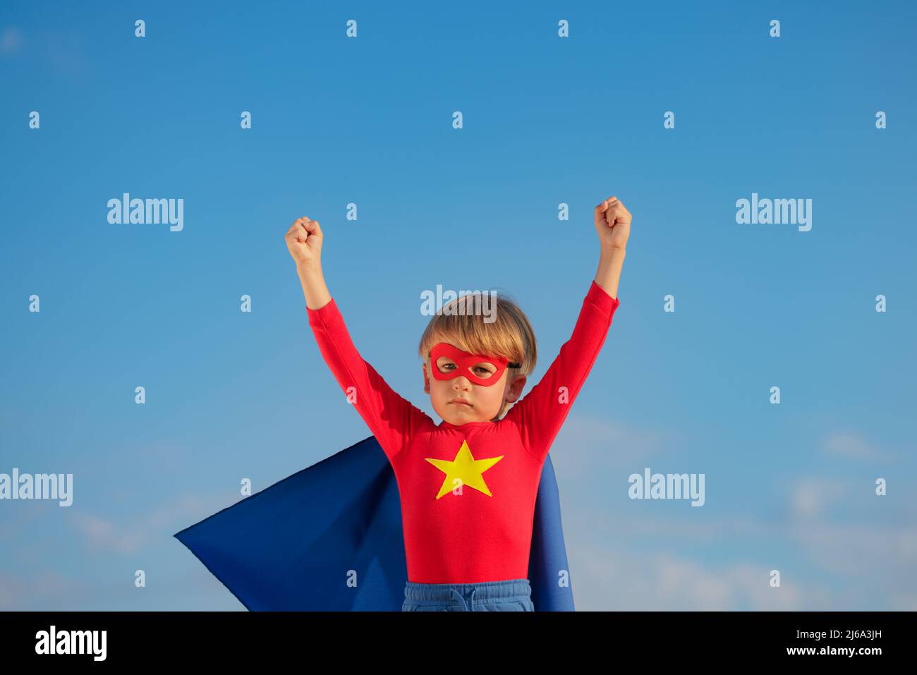 Superhero child playing outdoor. Super hero kid against blue summer sky ...