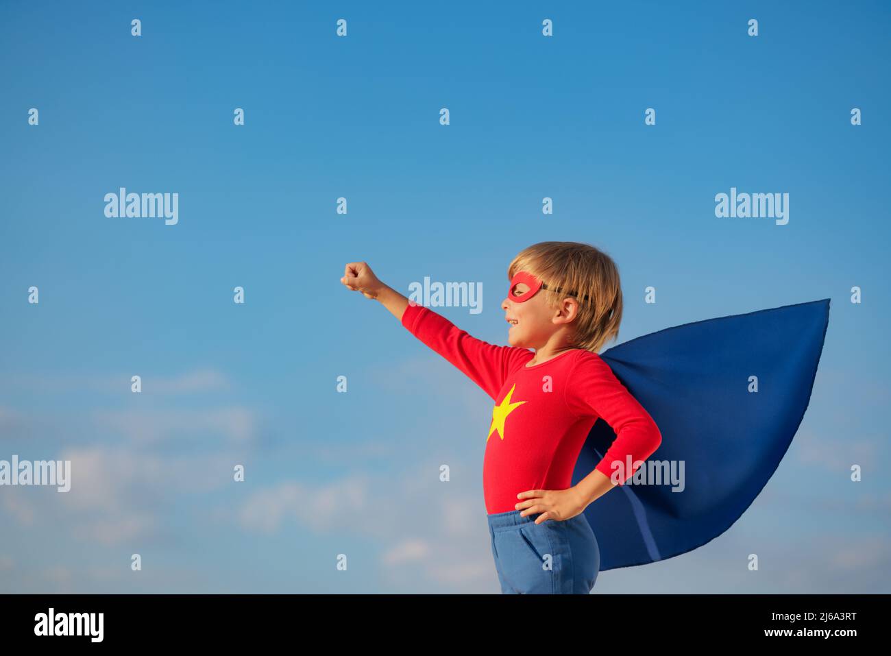 Superhero child playing outdoor. Super hero kid against blue summer sky ...