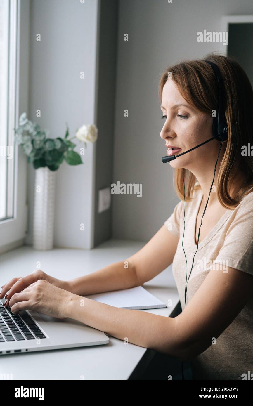 Vertical side view shot of female operator talking using headset and ...