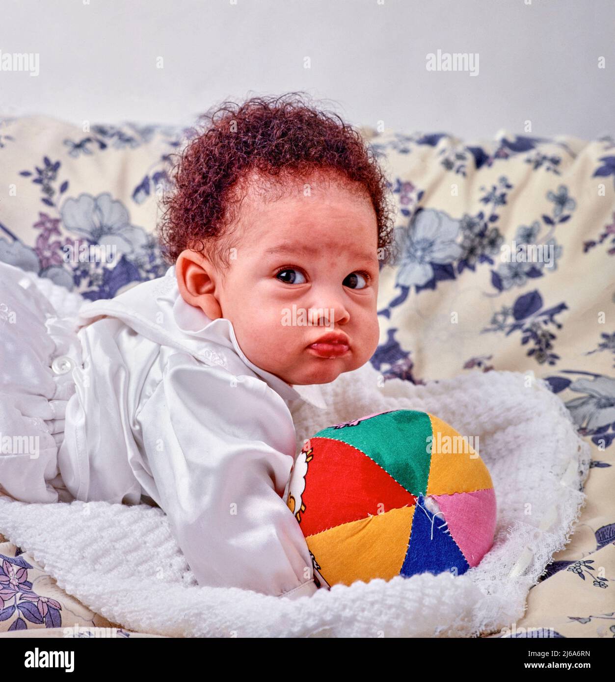 British Afro-Caribbean child (baby) with toys making hiding face Stock ...