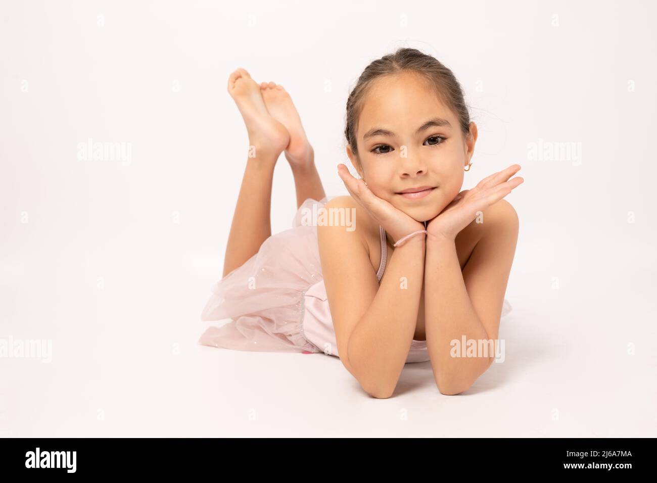 Little ballerina girl laying on the ground and posing for the camera ...
