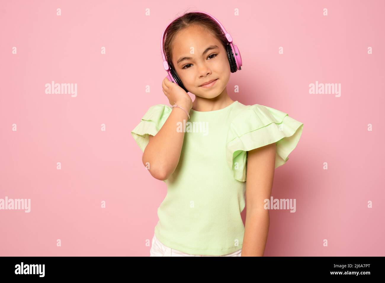 Beautiful cute happy little girl with headphones standing isolated over ...