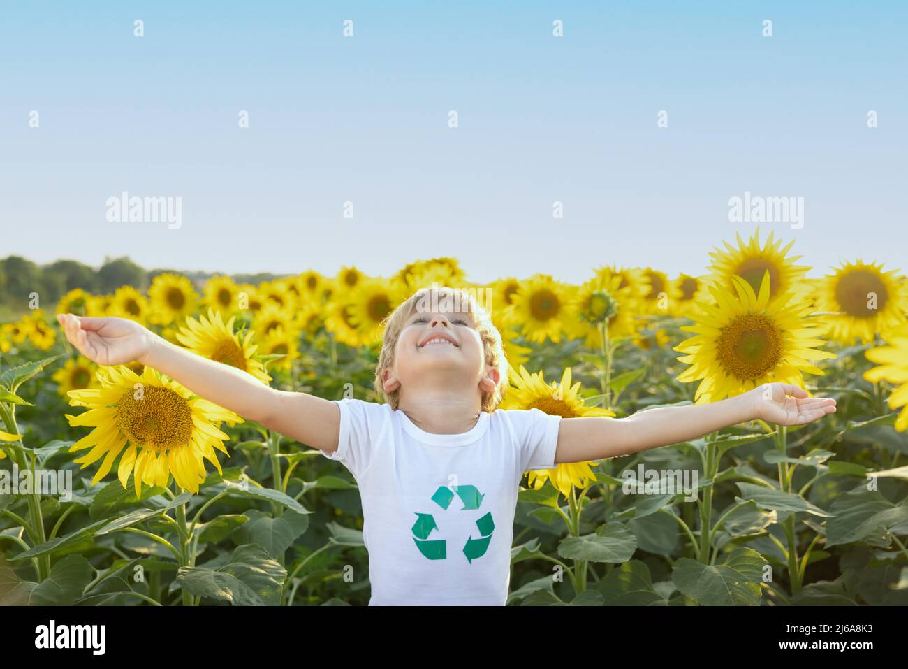 Happy child having fun in spring field of sunflowers. Outdoor portrait ...