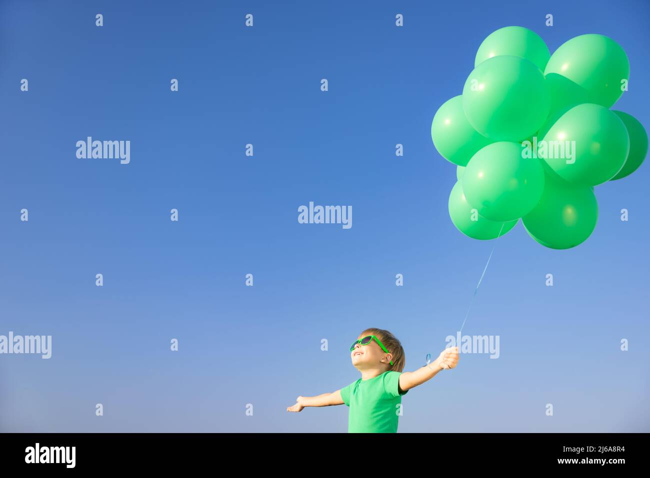 Happy child playing with bright green balloons outdoor. Kid having fun ...