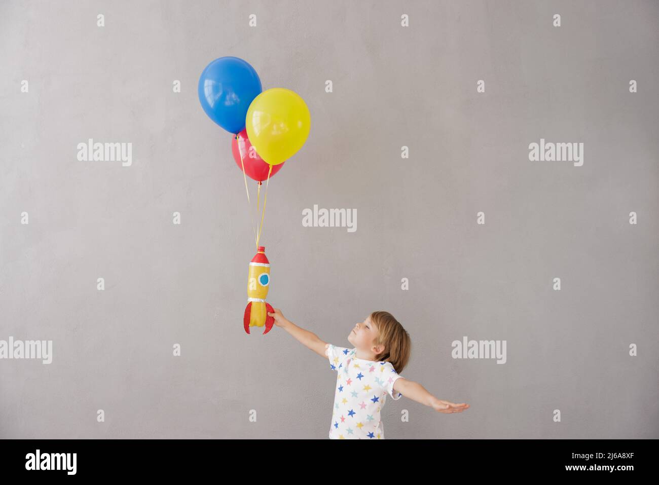 Happy child playing with toy rocket at home. Kid pretend to be ...