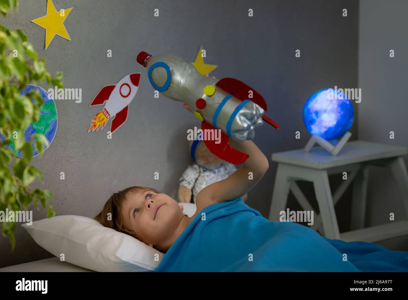 Happy child sleeping with toy rocket and teddy bear. Kid pretend to be ...