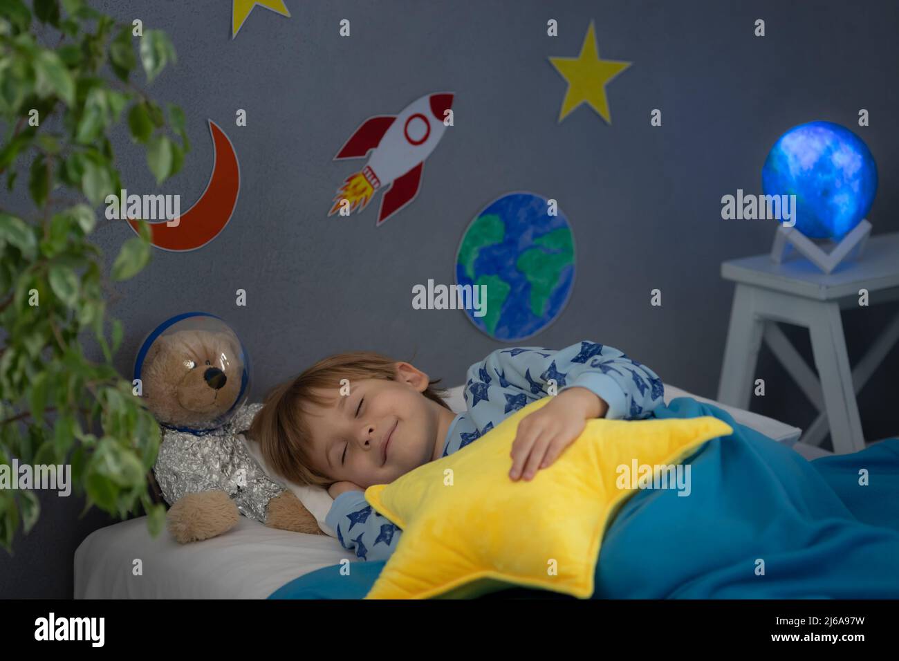 Happy child sleeping with toy rocket and teddy bear. Kid pretend to be ...