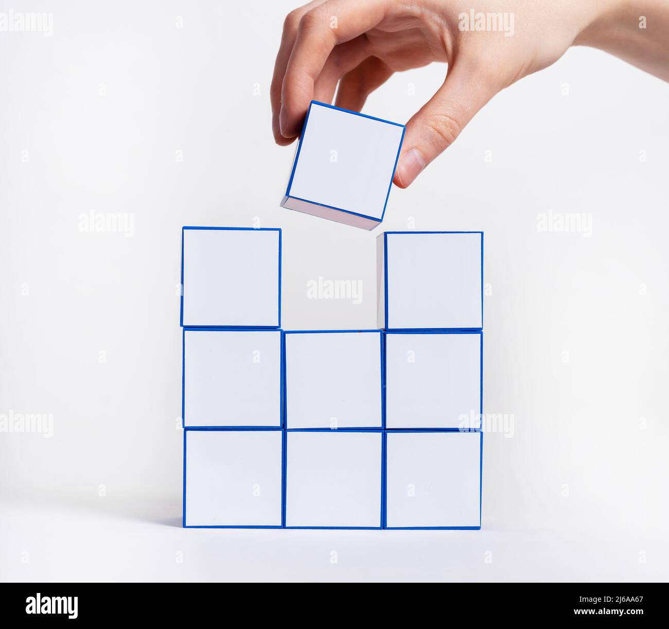 Hand stacking white cubes. Adding missing last element concept. High ...