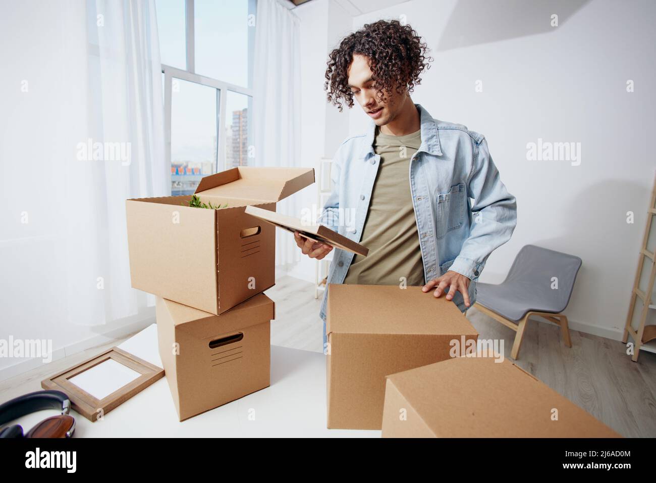 portrait of a man unpacking things from boxes in the room sorting ...