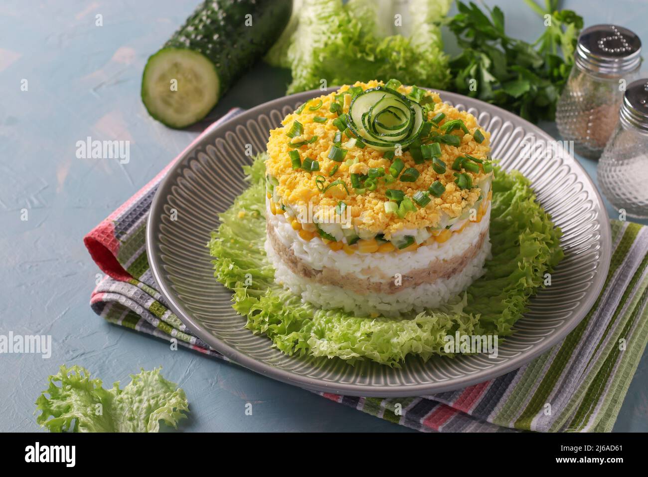 Festive puff salad with cod liver, rice, eggs, corn and cucumber on ...