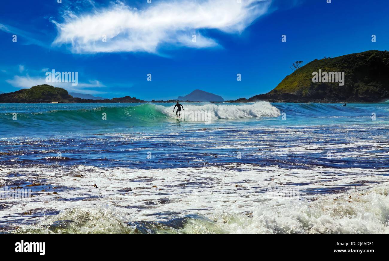 Beautiful bay with big waves, unrecognizable surfer, blue sunny sky ...