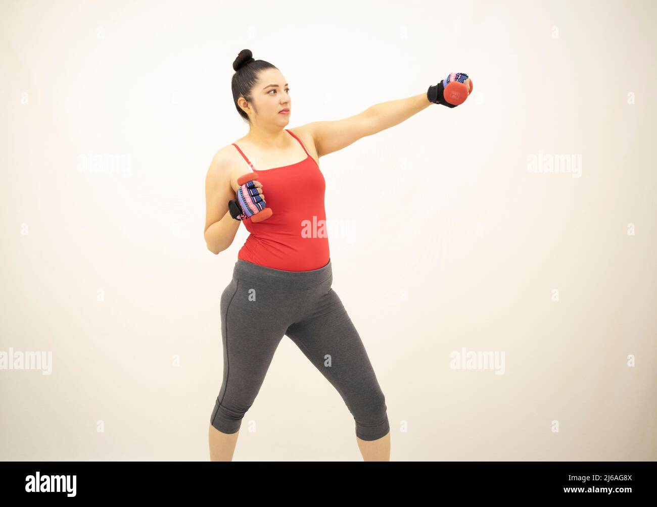 cute athletic woman wearing gray sportswear, red top, practicing boxing ...
