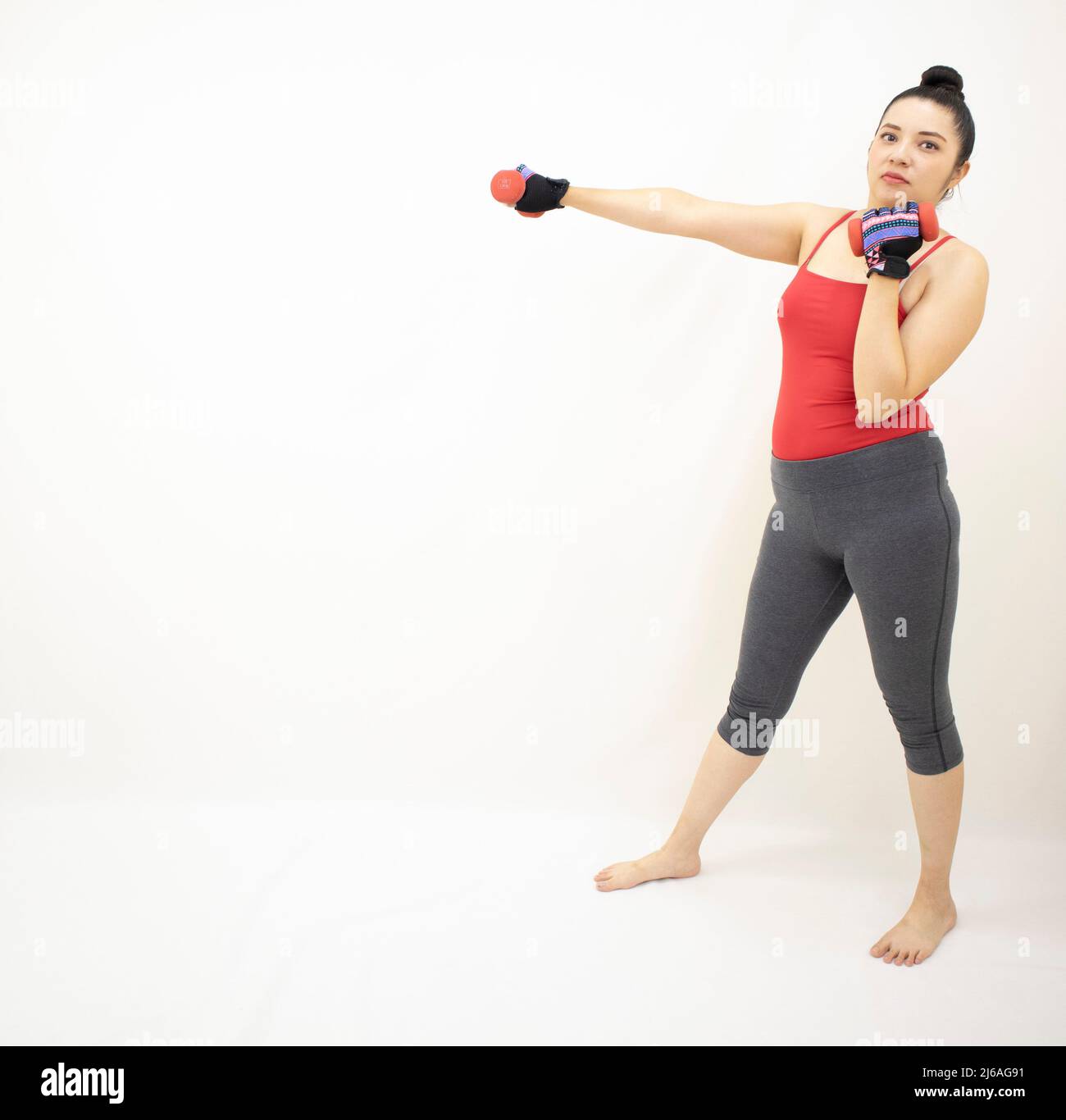 cute athletic woman wearing gray sportswear, red top, practicing boxing ...