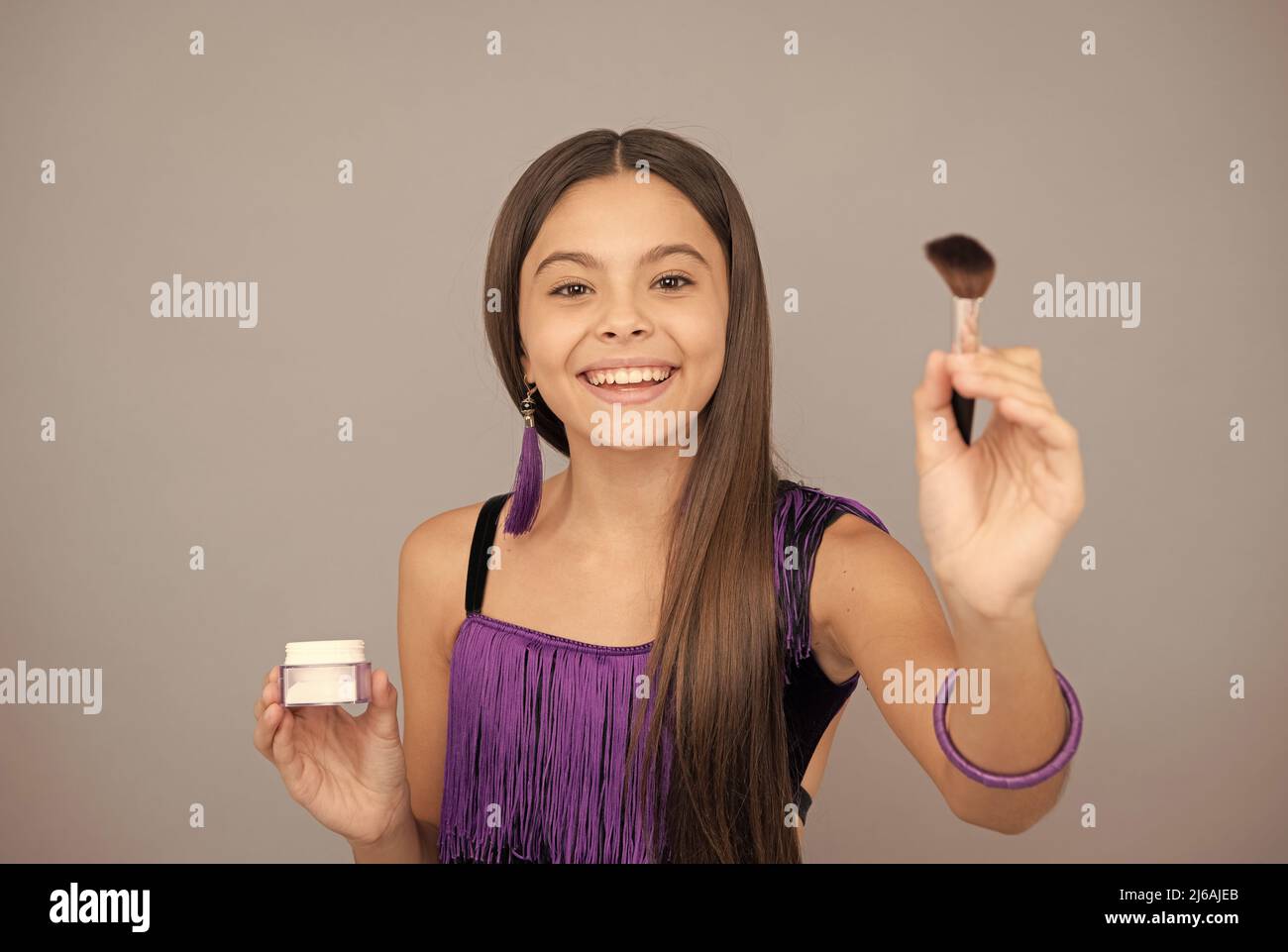 Happy make-up girl apply face powder with brush grey background, makeup ...