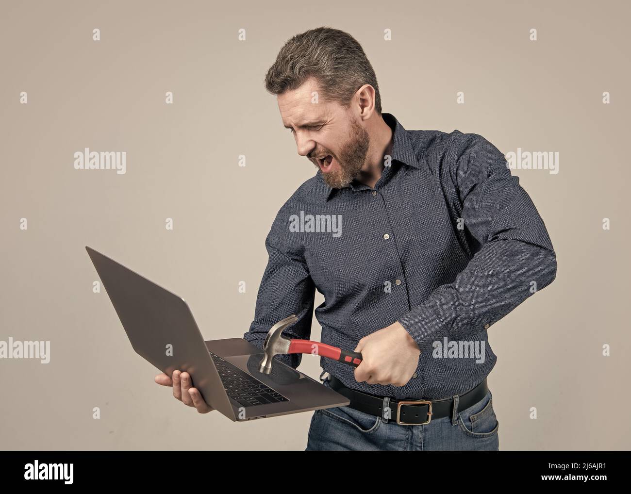Uncontrolled anger. Crazy man hit laptop with hammer. Feeling ...
