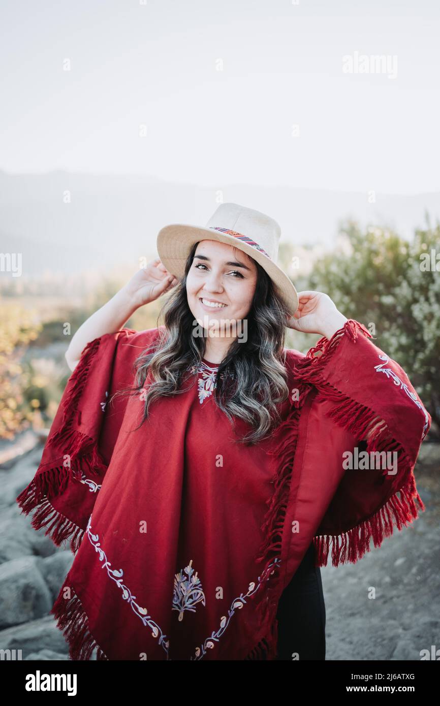 Traditional latin american woman wearing a red poncho and a hat seen ...