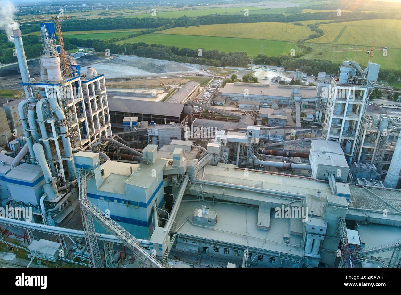 Aerial view of cement factory with high concrete plant structure and tower crane at industrial ...