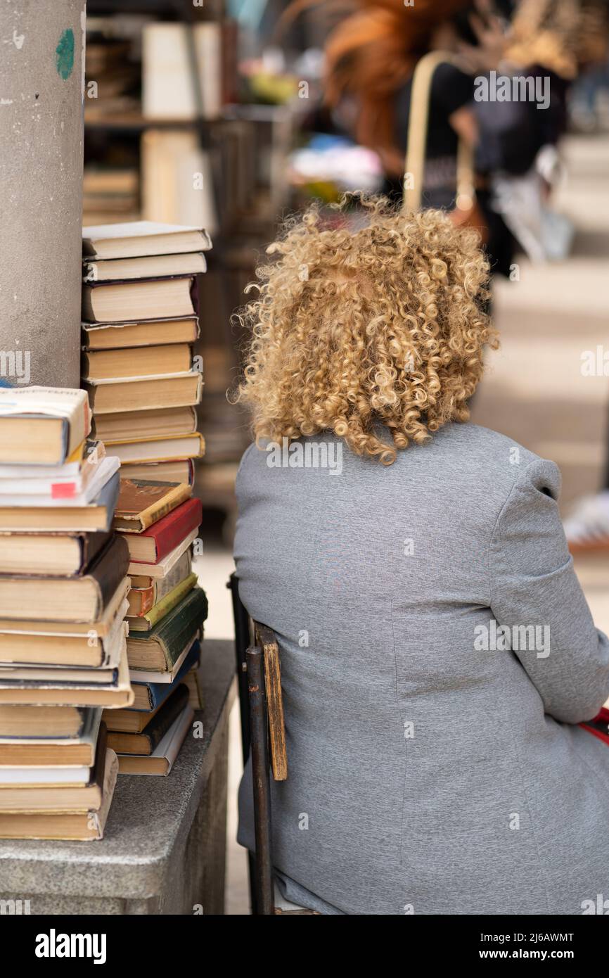 Senior woman selling old books on the city street. Female bookseller in ...