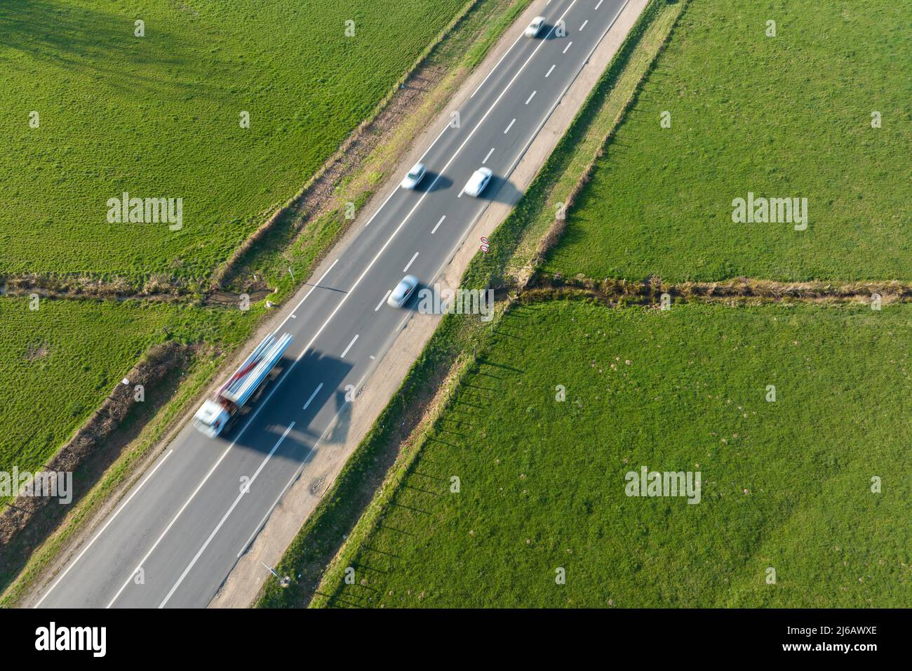 Aerial view of intercity road between green agricultural fields with ...