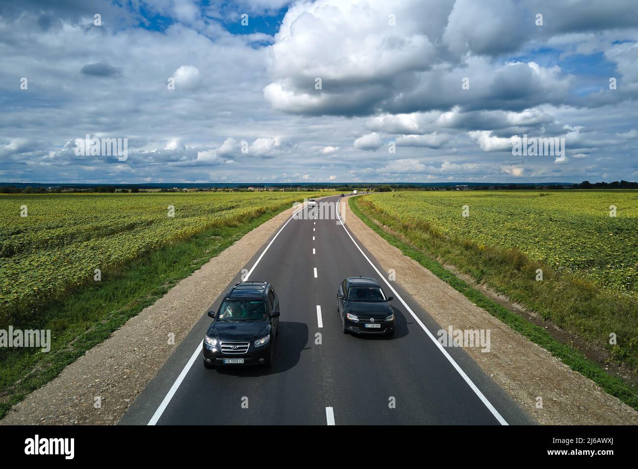 Aerial view of intercity road between green agricultural fields with ...