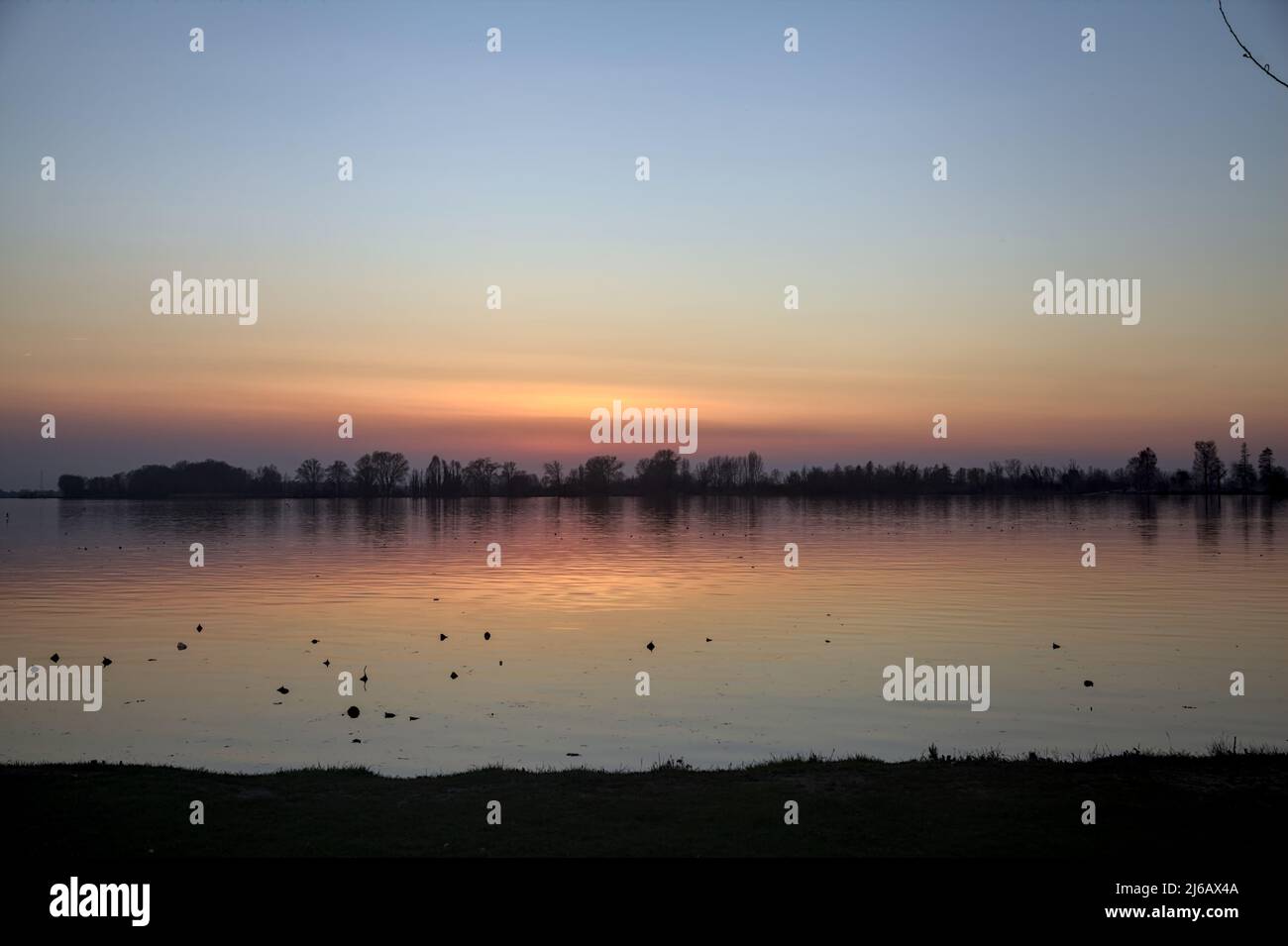 Lake at sunset seen from the shore Stock Photo - Alamy