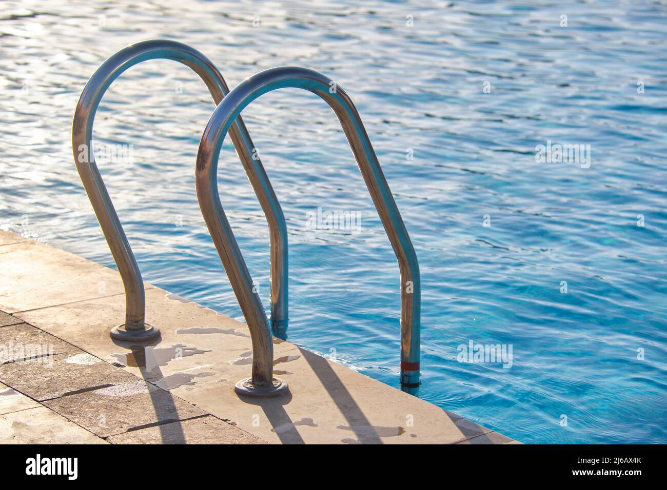 Close up of swimming pool stainless steel handrail descending into ...
