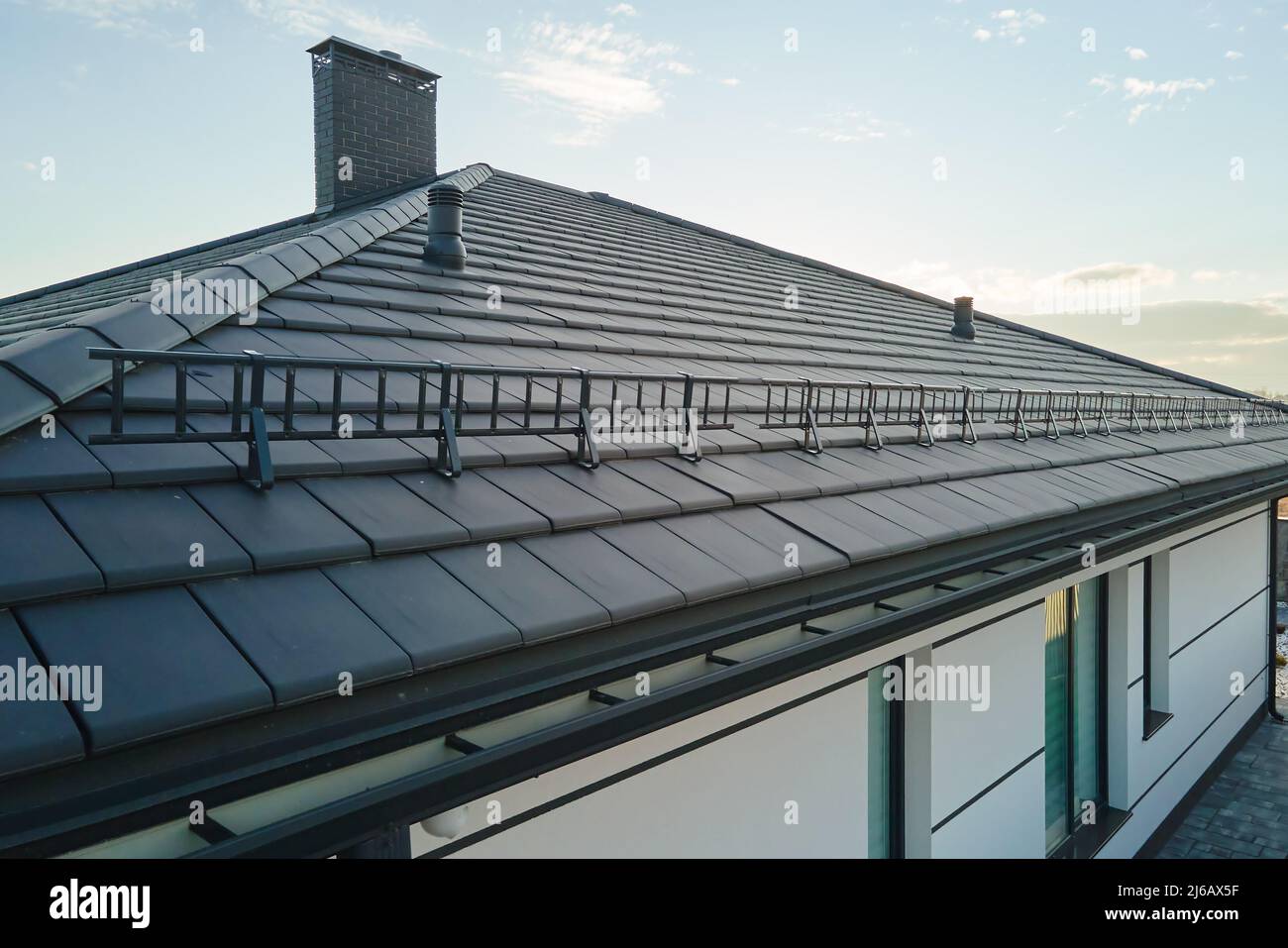 Closeup snow guard for safety in winter on house roof top covered with ...