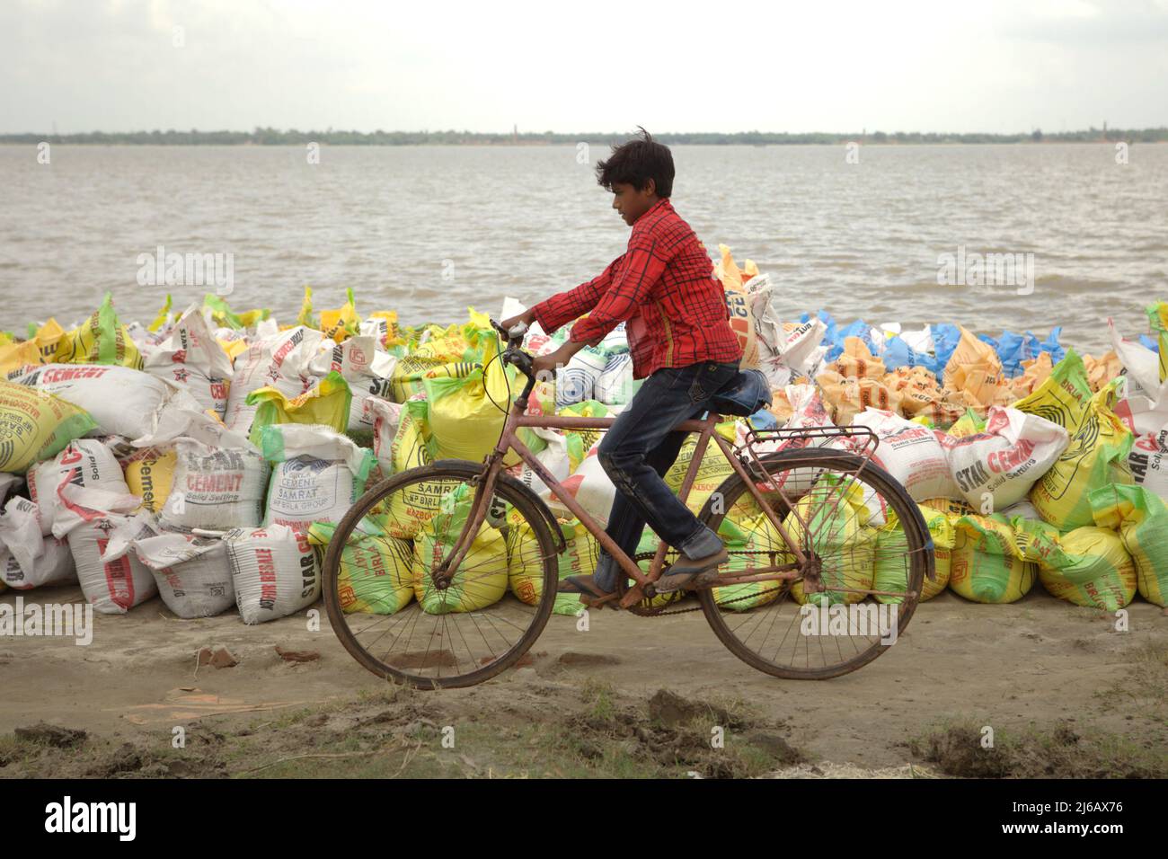 A child riding bicycle on the bank of Rupnarayan river in front of ...