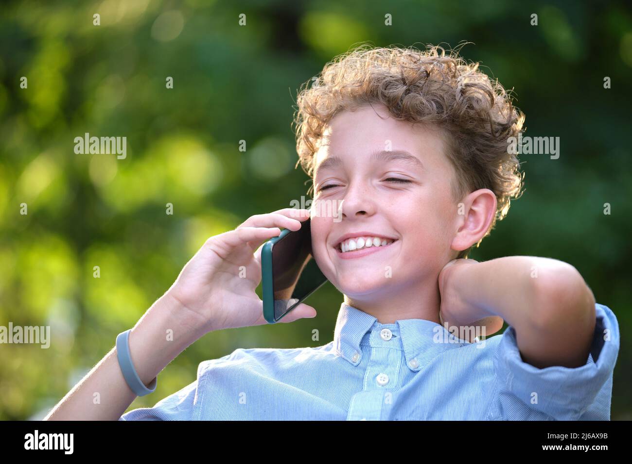 Happy young boy talking on cellphone outdoors in summer park Stock ...