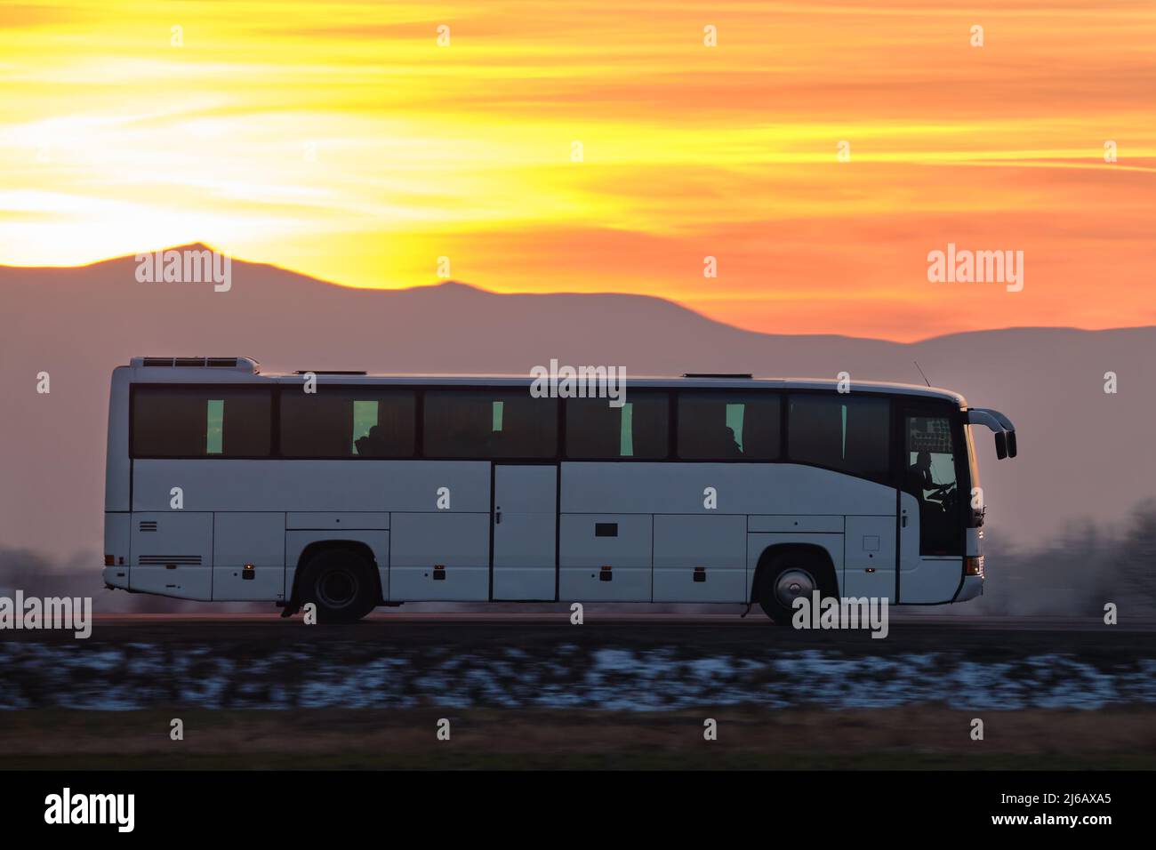 Intercity passenger bus driving on highway road in evening Stock Photo ...