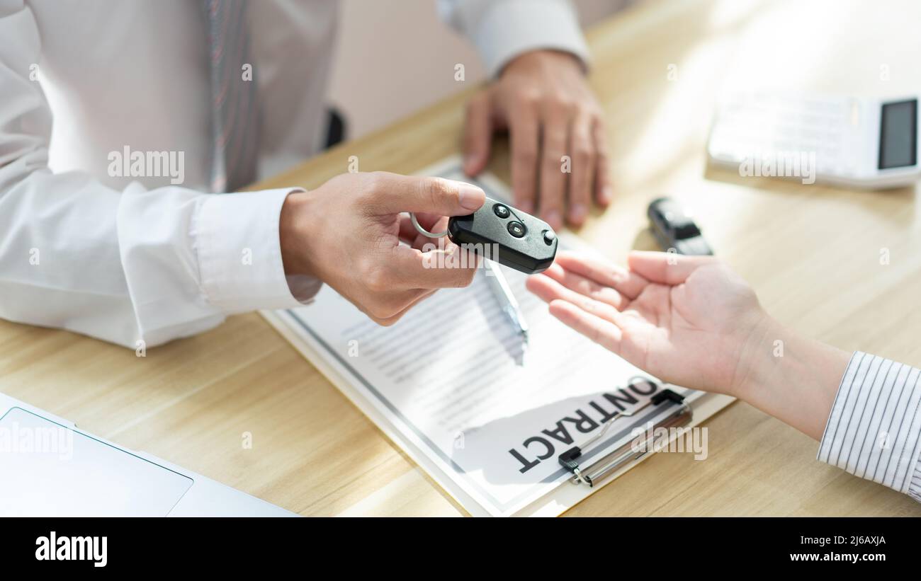 Insurance concept the car dealership giving a car key to his customer ...