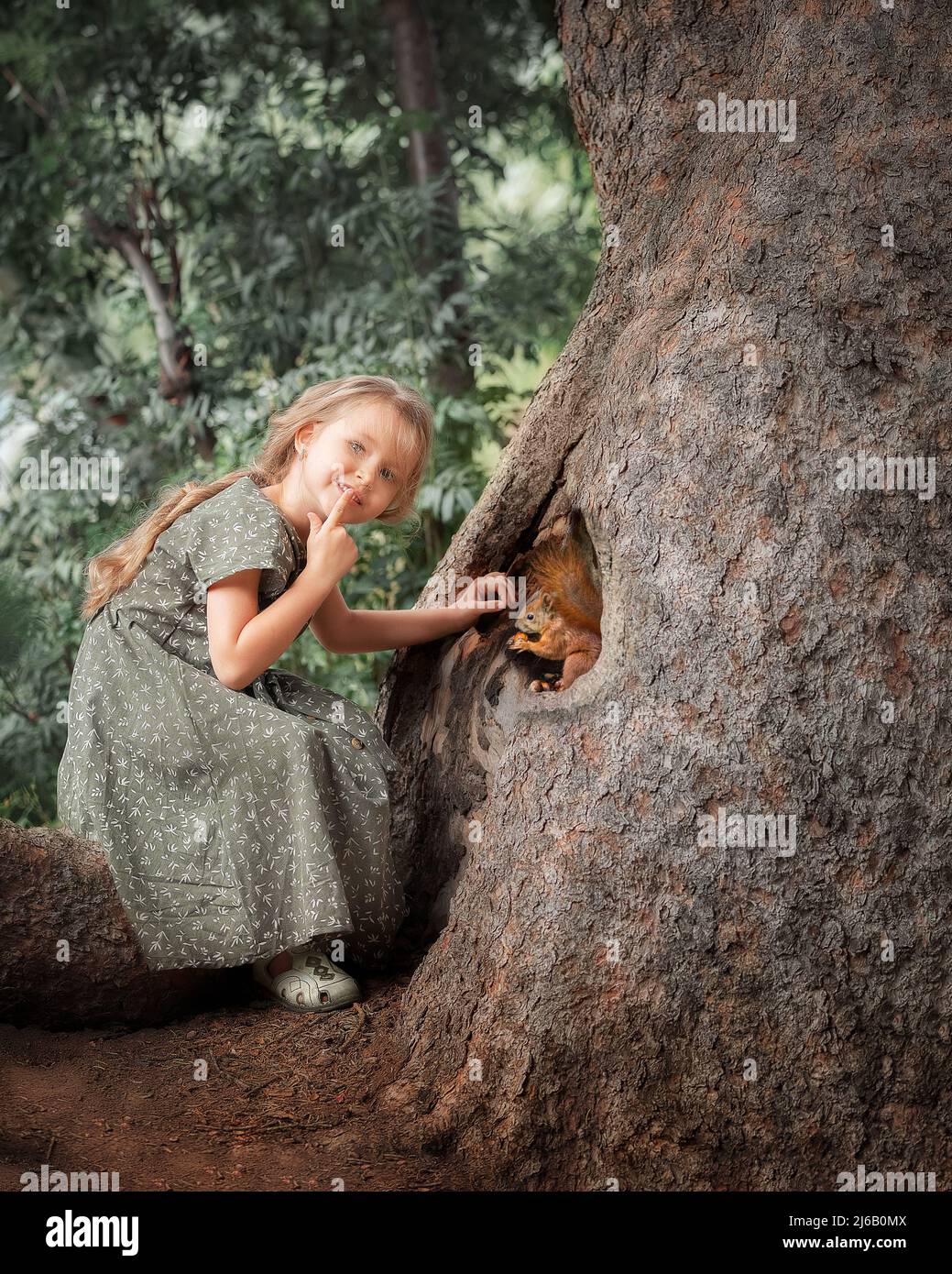 Portrait of adorable little kid girl near the tree with squirrel on it ...