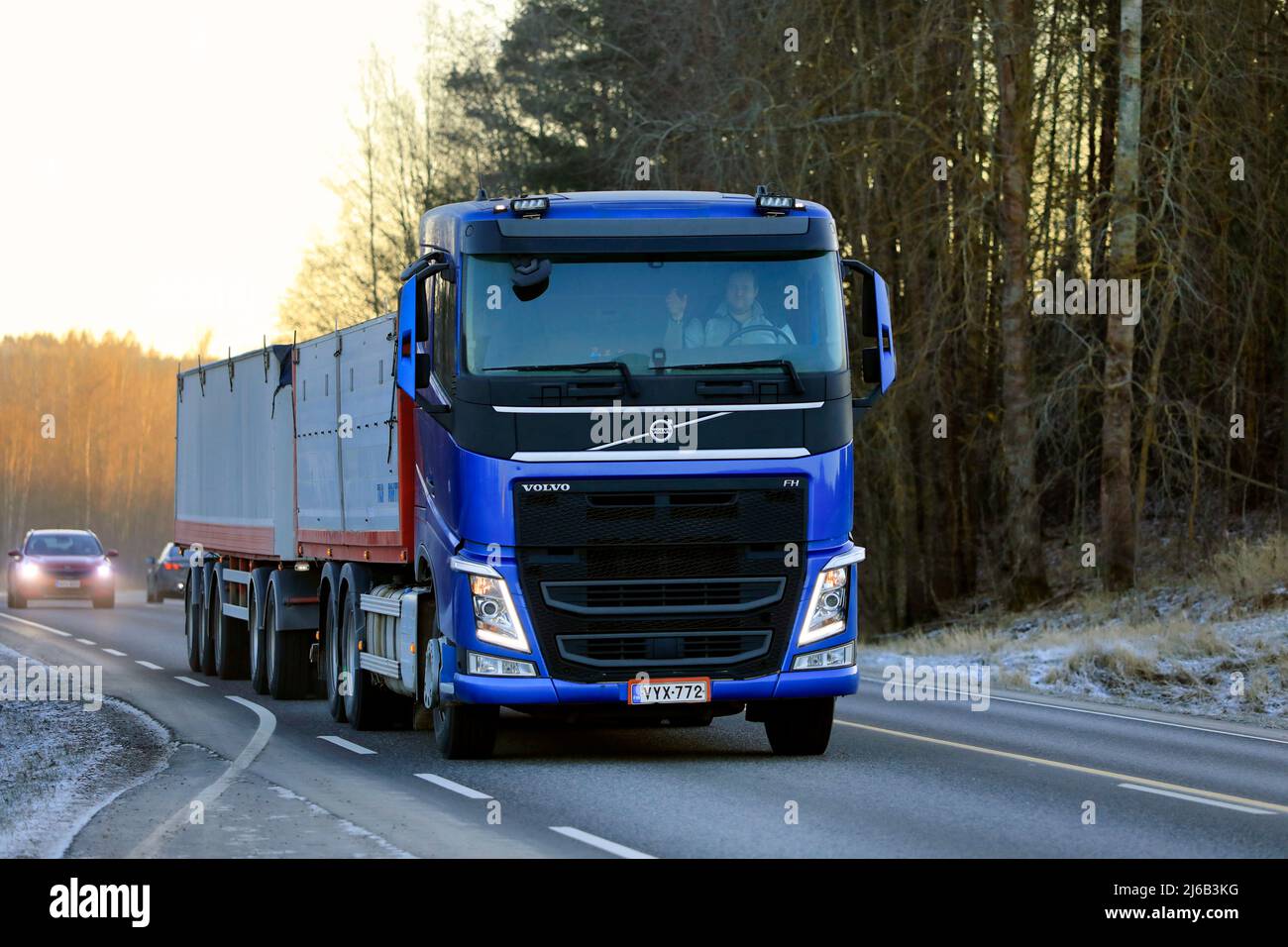 Blue Volvo FH truck pulls trailer in highway 52 traffic at winter dusk ...