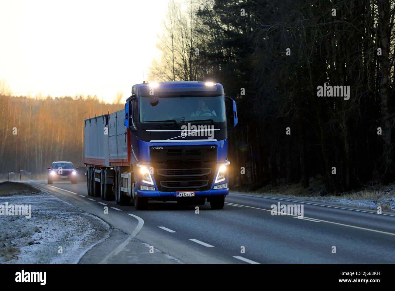 Blue Volvo FH truck pulls trailer along highway 52 at winter dusk, high ...