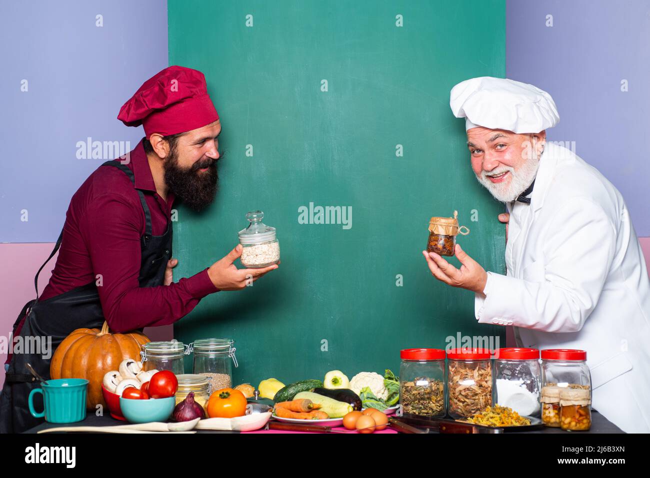 Two smiling male chefs, cooks or bakers with menu blank board. Kitchen ...
