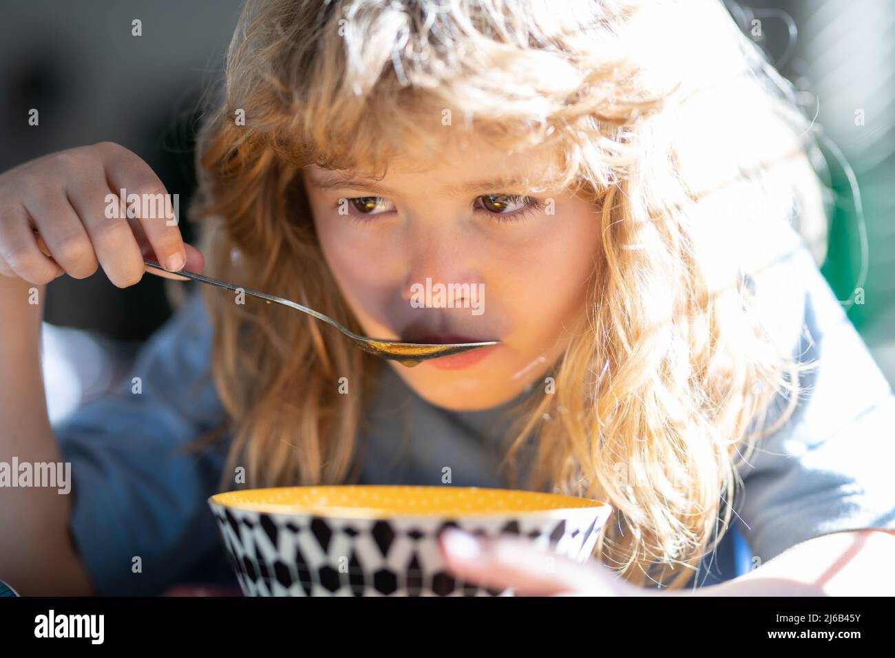 Cute child eats food itself with spoon. Little kid are eating soup ...
